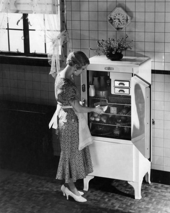 In 1913 A woman placing a dish of food in her refrigerator. - NSF Media